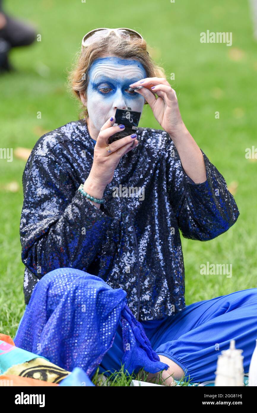 London, UK. 29th Aug, 2021. A protester applies stage makeup to her ...