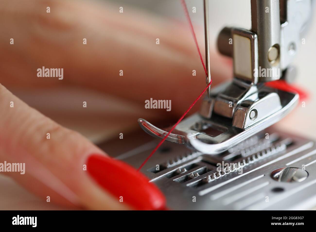 Hands pulling red thread in sewing machine needle Stock Photo - Alamy