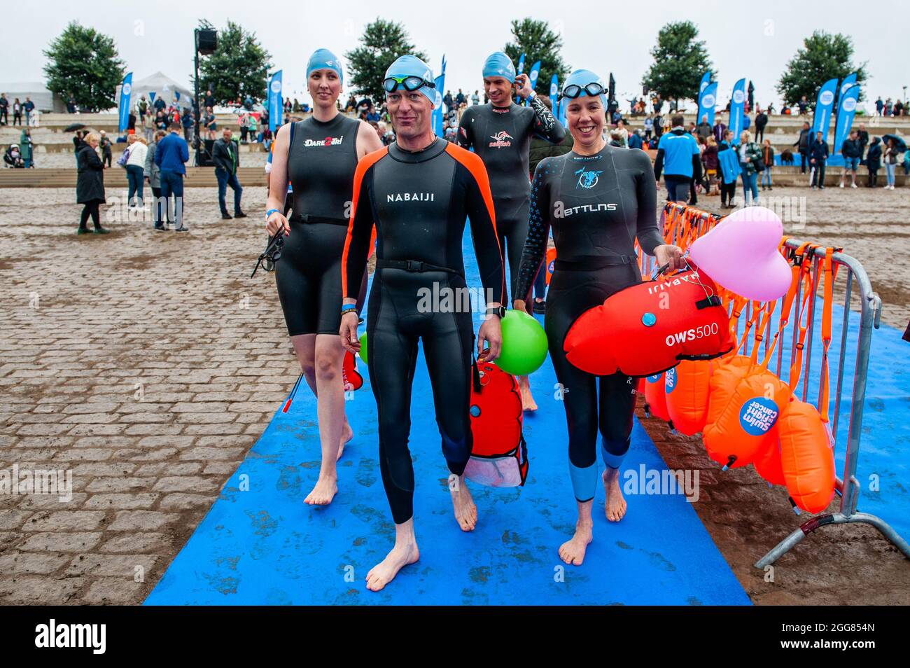 A group of people is seen wearing neoprene wetsuits and heart balloons ...