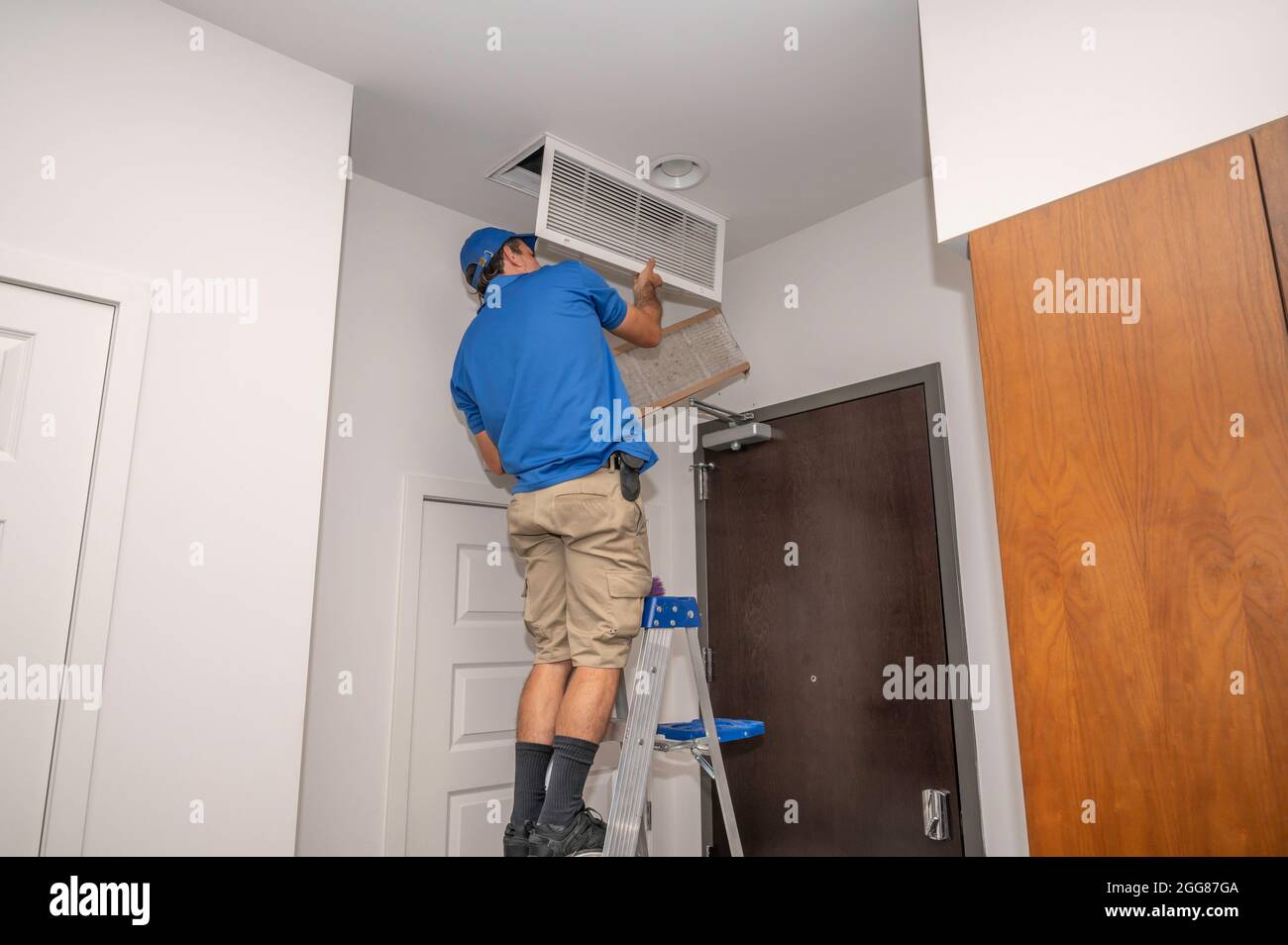 HVAC technician on ladder changing an air filter Stock Photo - Alamy