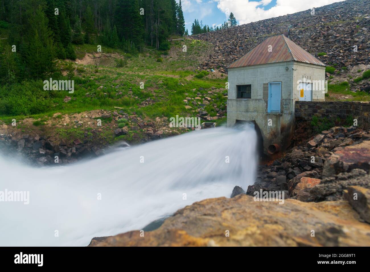 Water coming out of dam control building at mountain lake, United ...