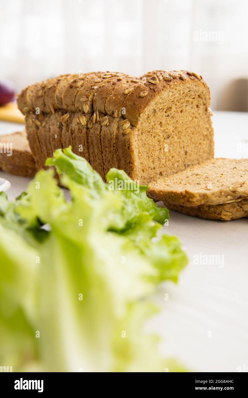 closeup to a sliced whole wheat bread mold next to a lettuce, healthy ...