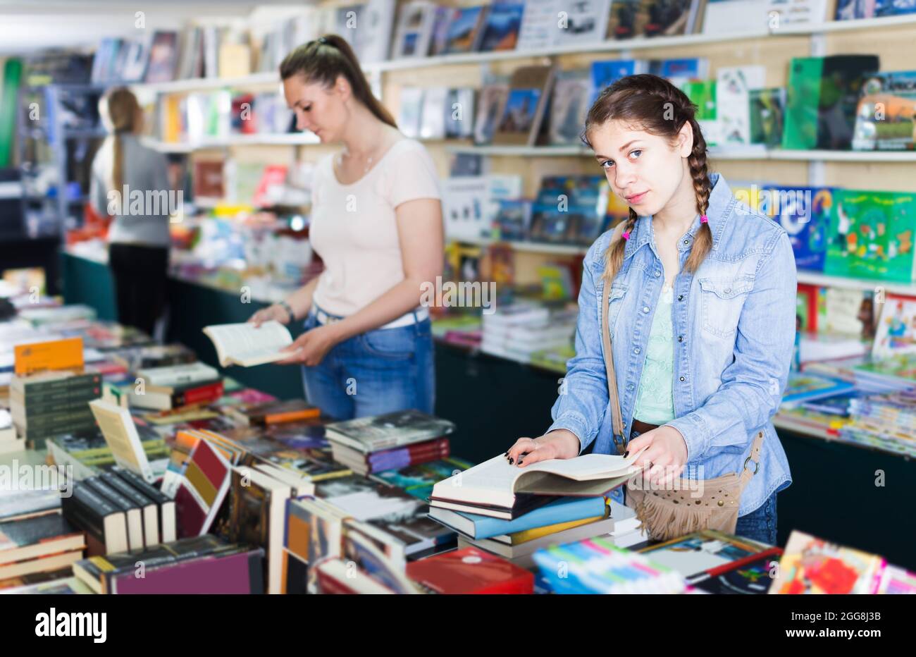 glad woman showing open book to positive girl in book boutique Stock ...