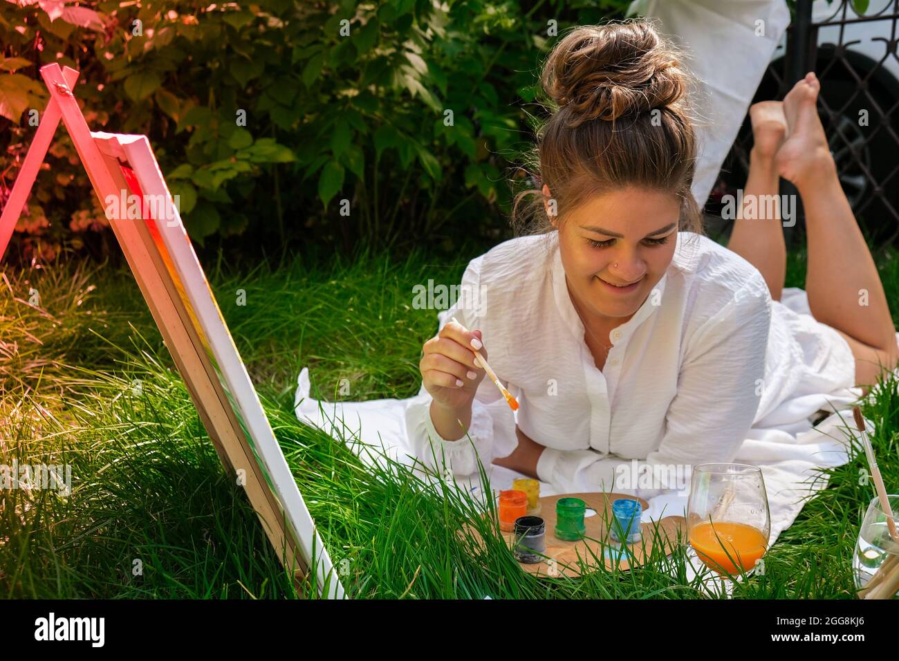 Artist painting on the easel outdoors in the garden. Open air outdoor ...