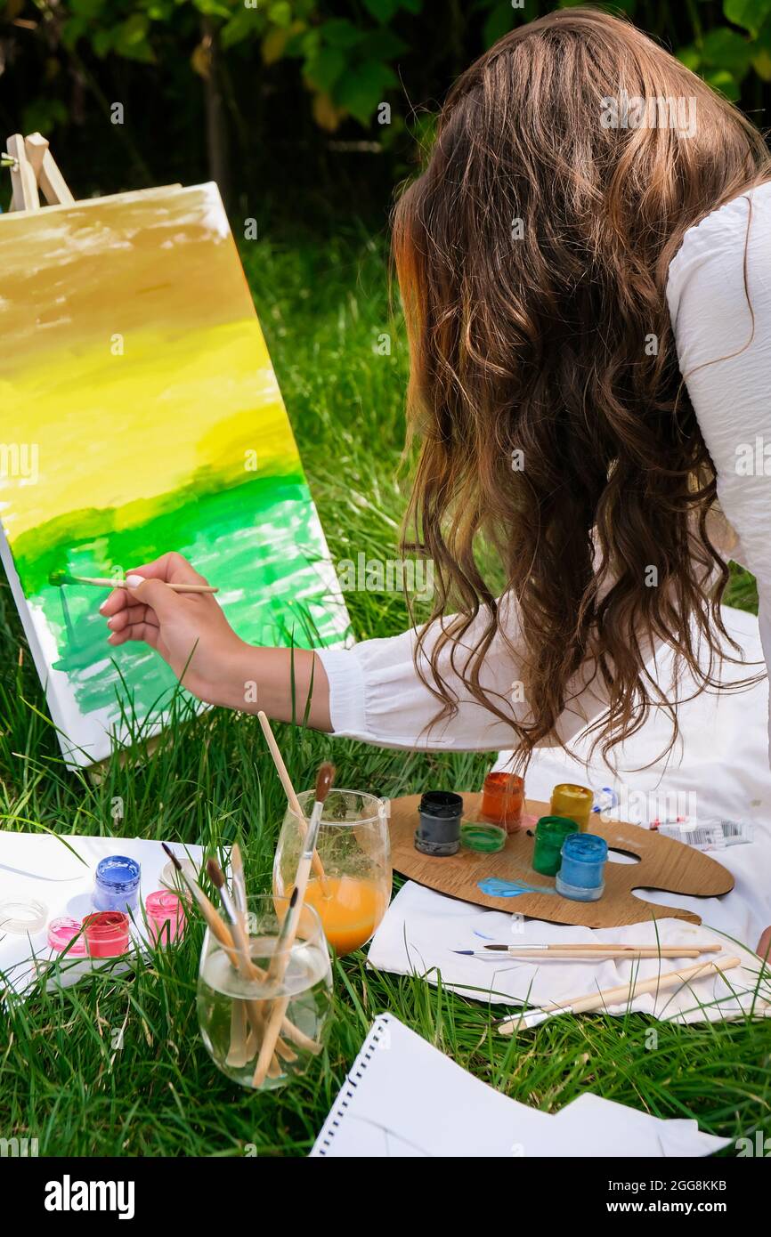 Artist painting on the easel outdoors in the garden. Open air outdoor ...