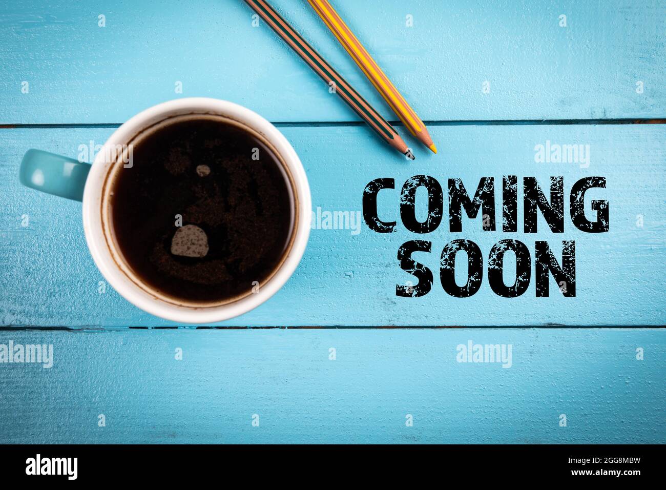 Coming Soon. Coffee mug and pencils on office desk Stock Photo - Alamy