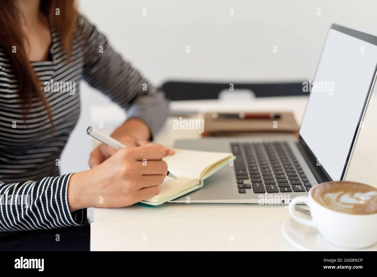 Side view, businesswoman taking notes on notebook while looking at ...