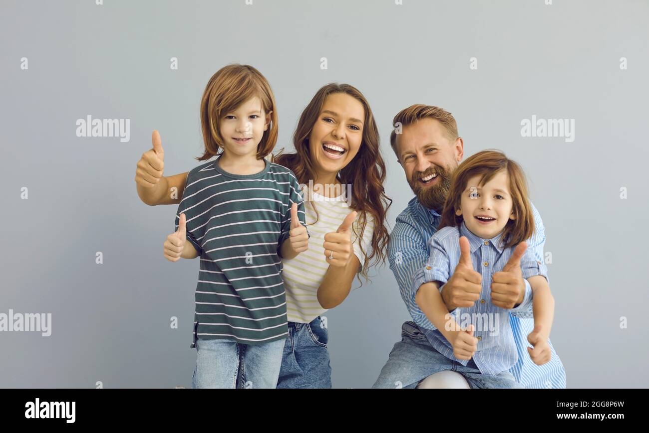 Studio portrait of happy mother, father and children smiling and giving ...