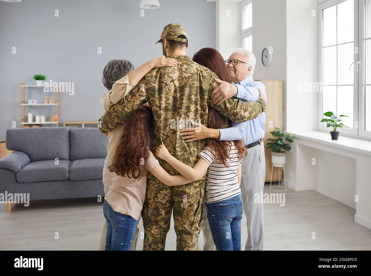 Happy family hugging their veteran father who has come back home from ...
