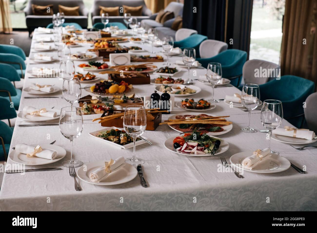 Long table before celebration in restaurant, empty glasses and ...