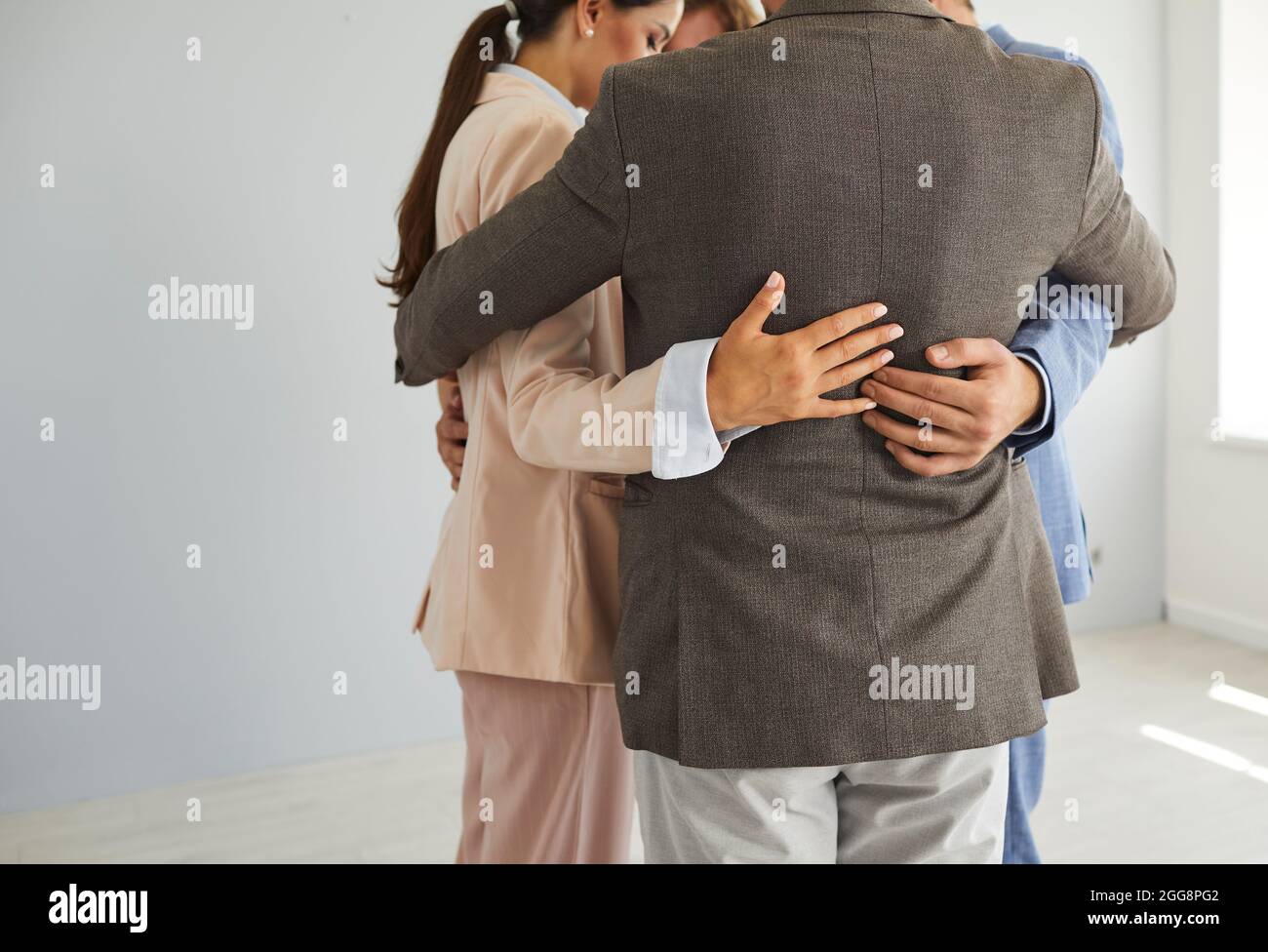 Group of supportive business colleagues standing together and hugging ...