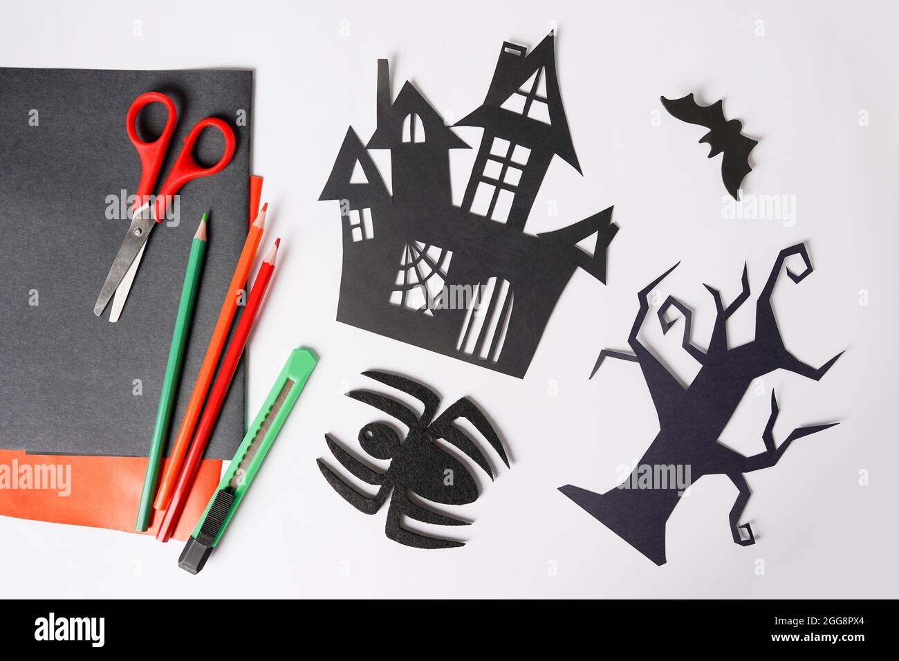 The child create Halloween paper decor tree, spider and house. scissors ...