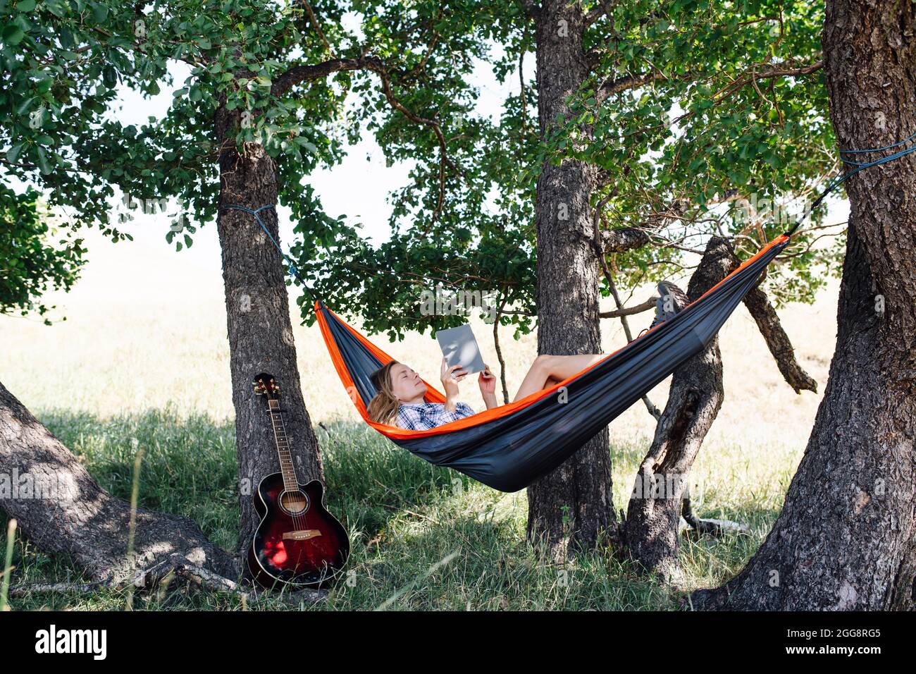 Napping woman lying in a hammock, slugging in a shadow, between two big ...
