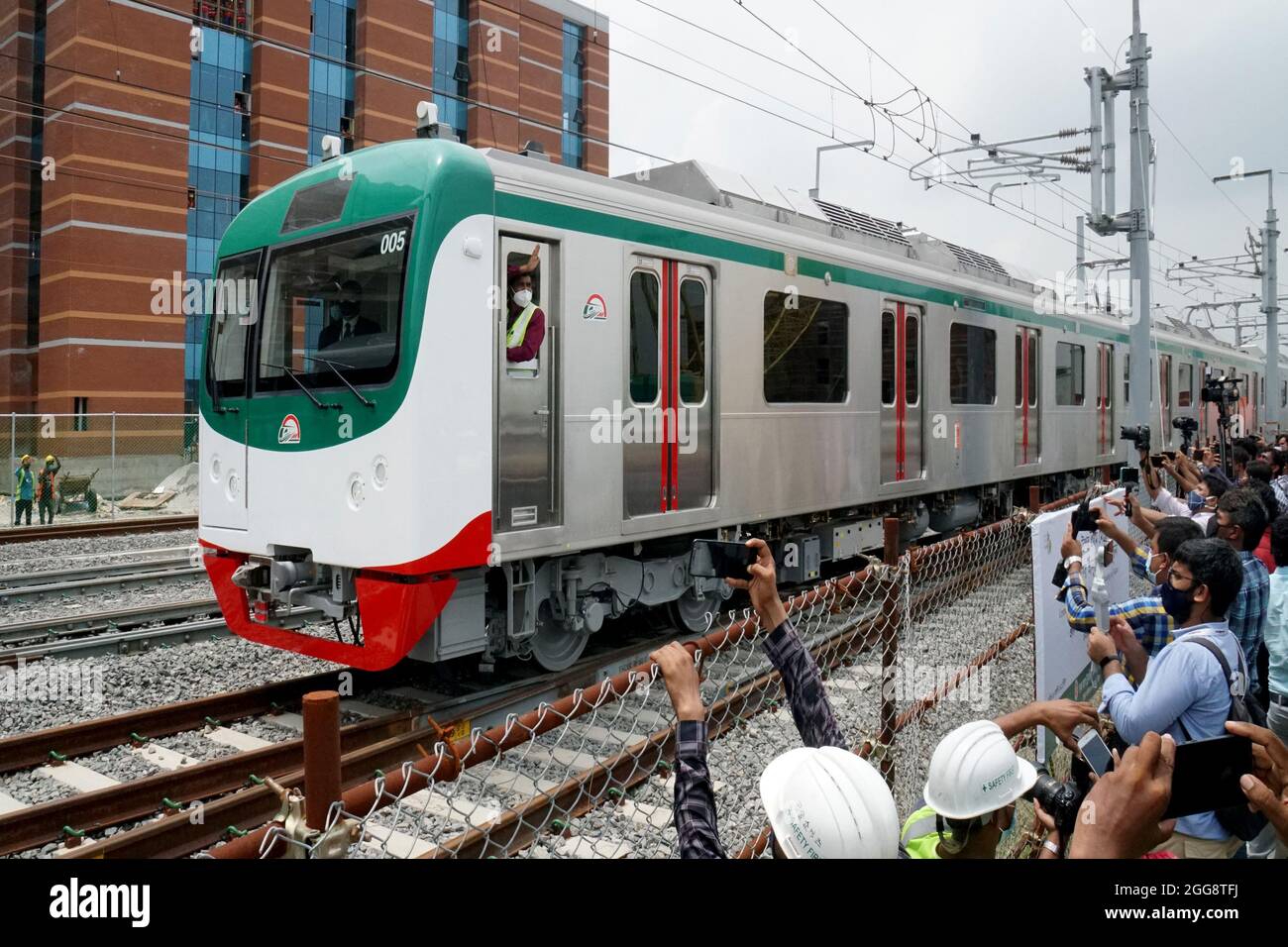 Dhaka. 30th Aug, 2021. People witness the first trial run of Bangladesh's metro rail service in ...