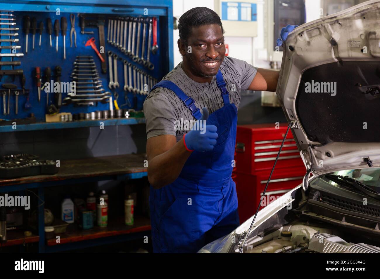 Professional american mechanic man in uniform repairing car engine ...