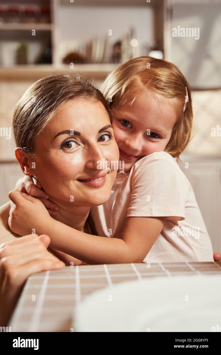 Cute girl giving a hug to woman in the kitchen Stock Photo - Alamy