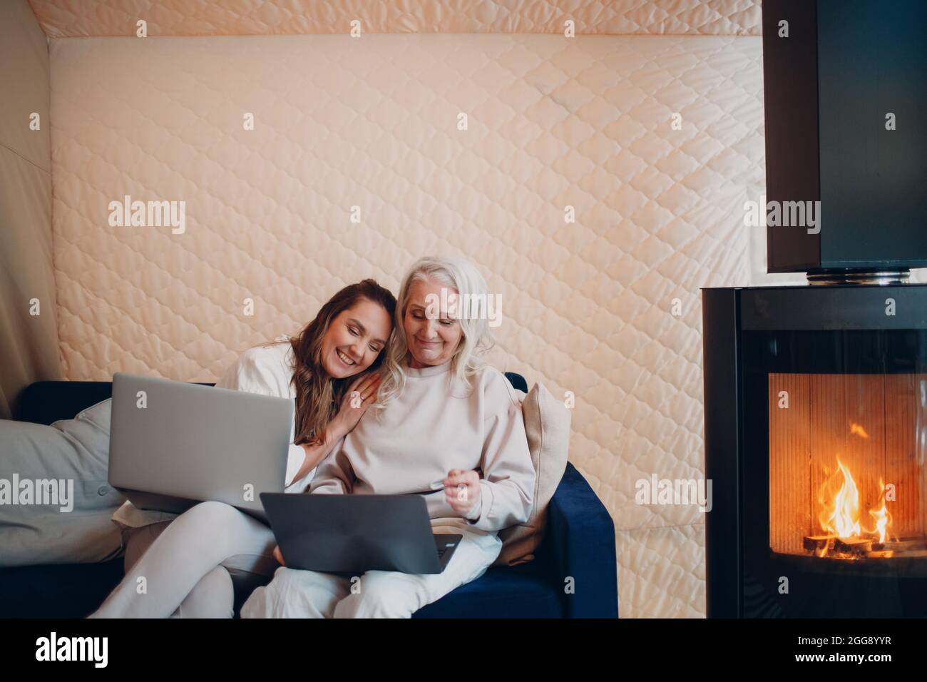 Senior and young woman using computer laptop at sofa. Mom and daughter ...