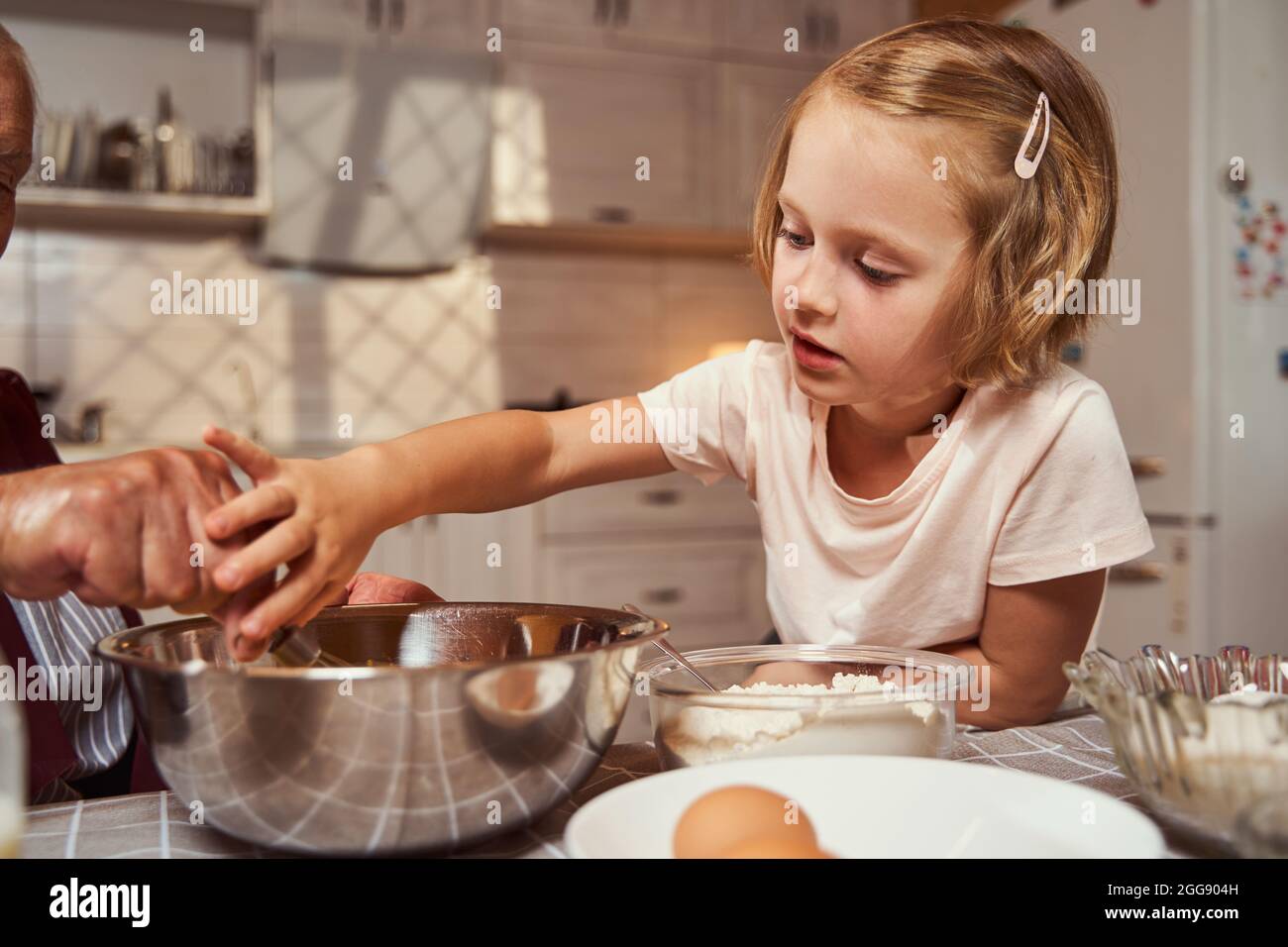 Adult woman taking whisk from girl hand Stock Photo - Alamy
