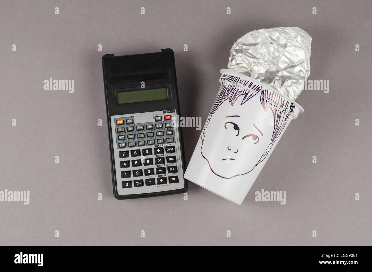 Calculator and a surprisingly human face painted on the plastic cup ...