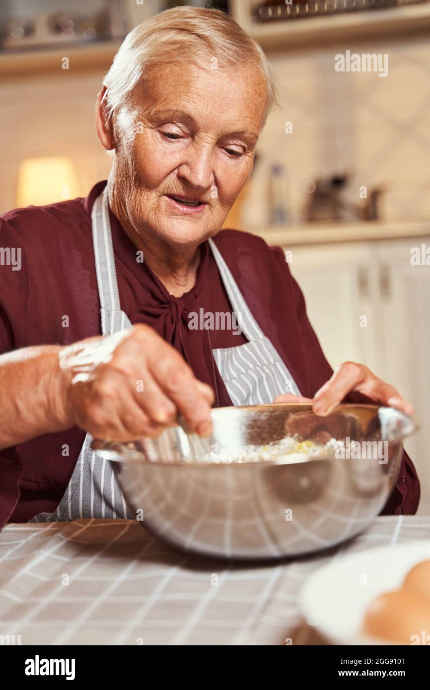 Elderly lady stirring mix of flour and eggs in bowl Stock Photo - Alamy