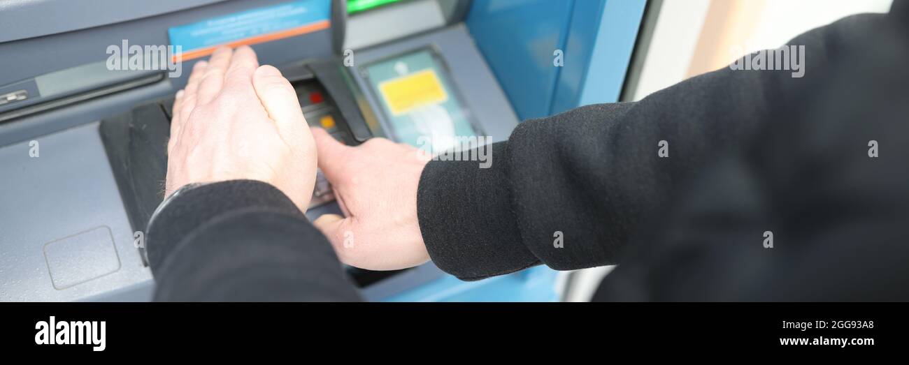 Man entering pin code at ATM and covering it with his hand closeup ...