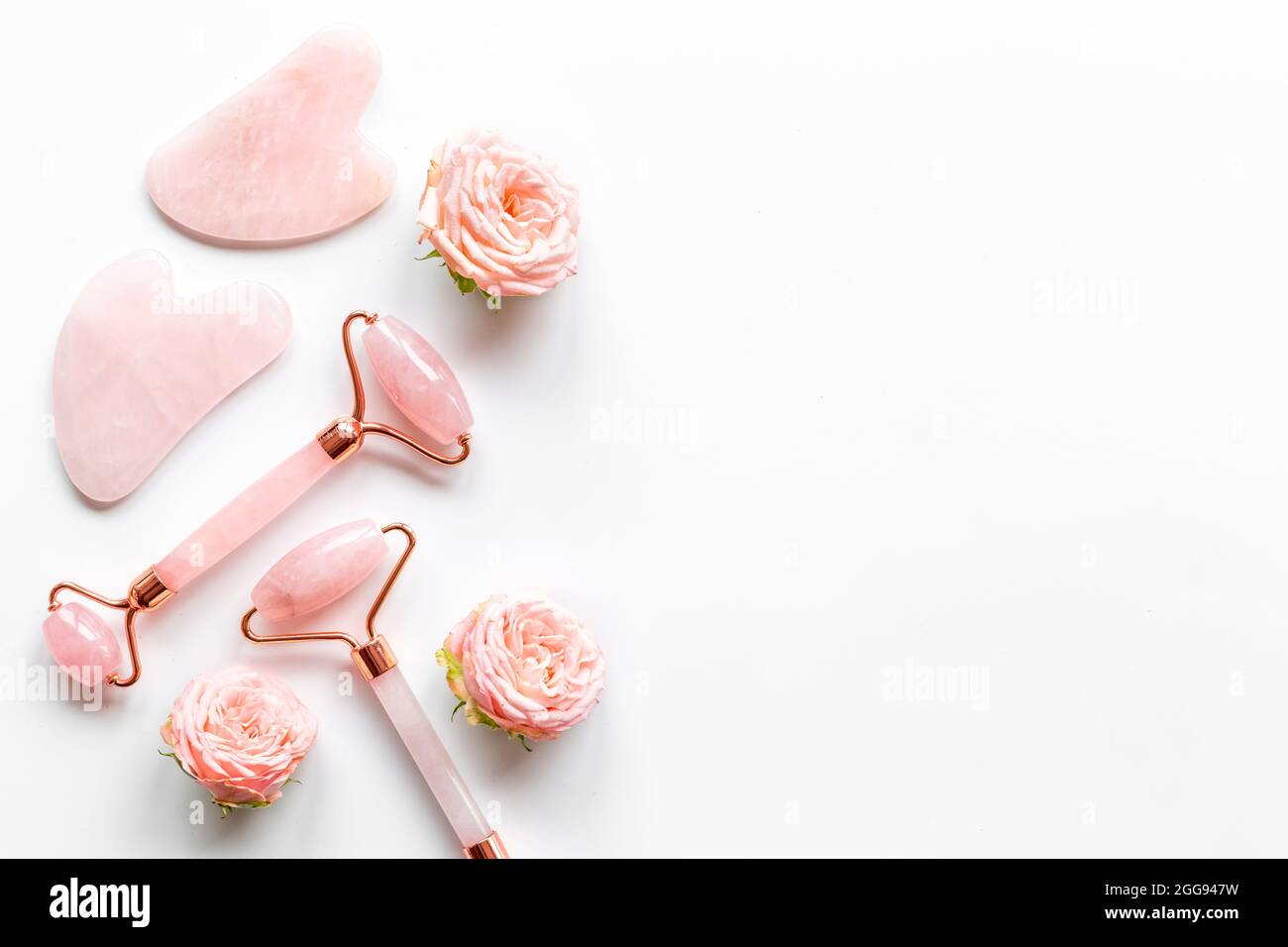 Pink gua sha massage stone and face roller with rose flowers Stock ...