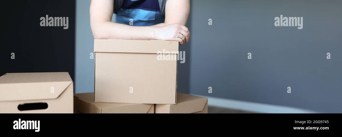 Man in overalls putting his hands on cardboard boxes closeup Stock ...