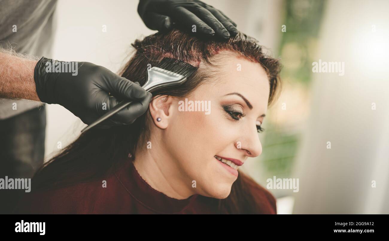 Hairdresser coloring female client hair Stock Photo - Alamy
