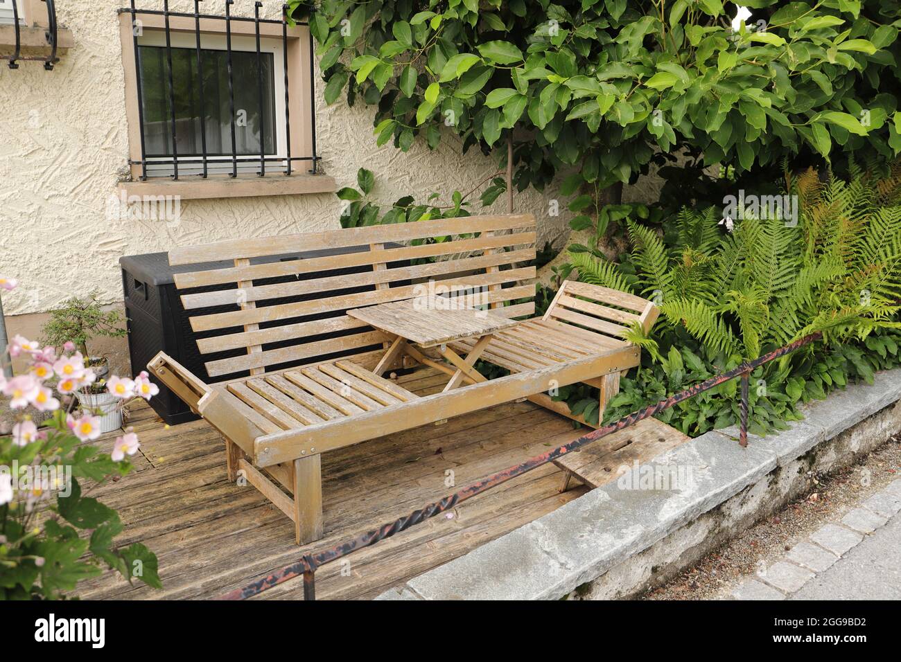 a garden bench in front of a house with plants Stock Photo - Alamy
