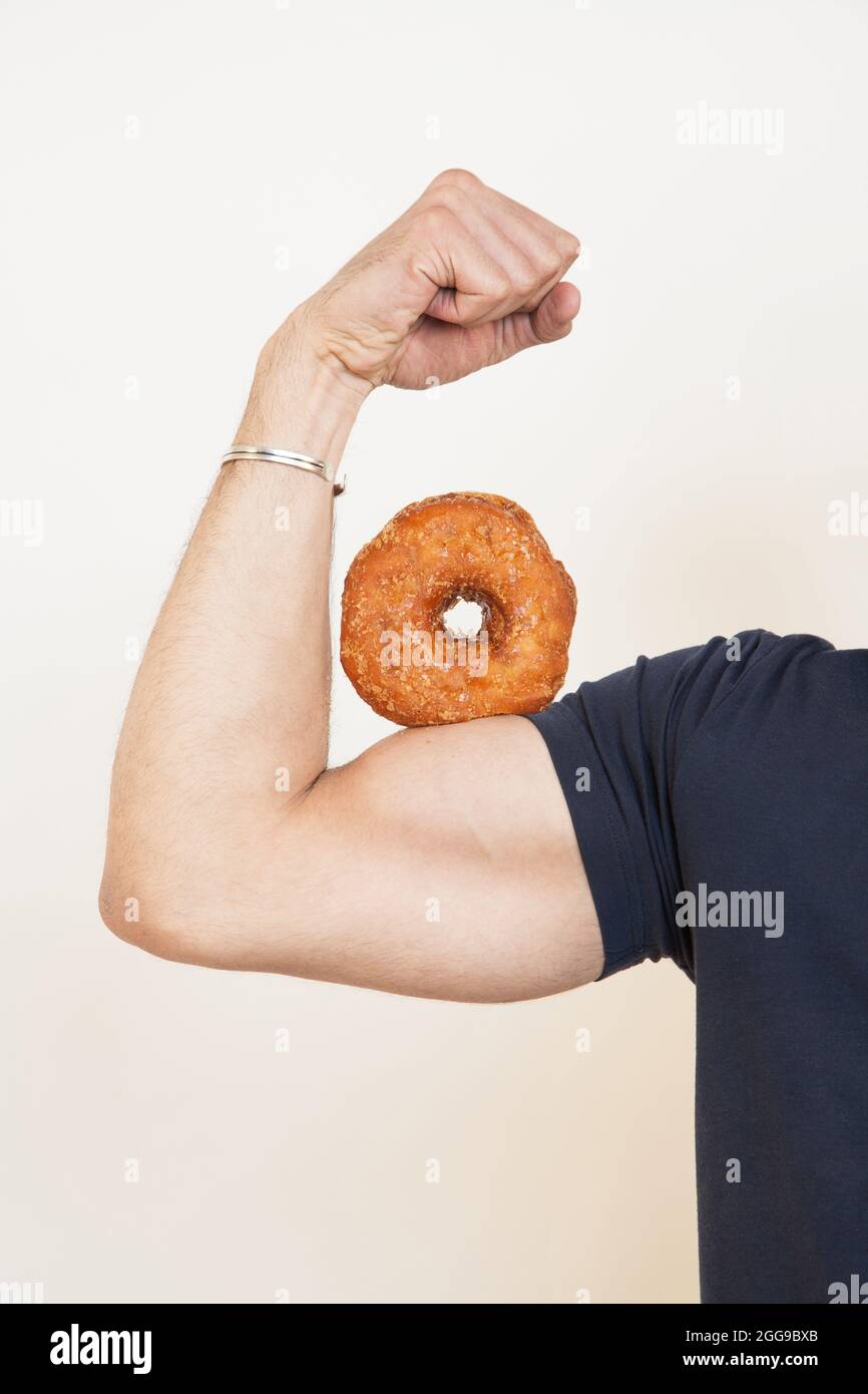 Body builder placing donut on his muscular bicep on cheat day Stock ...