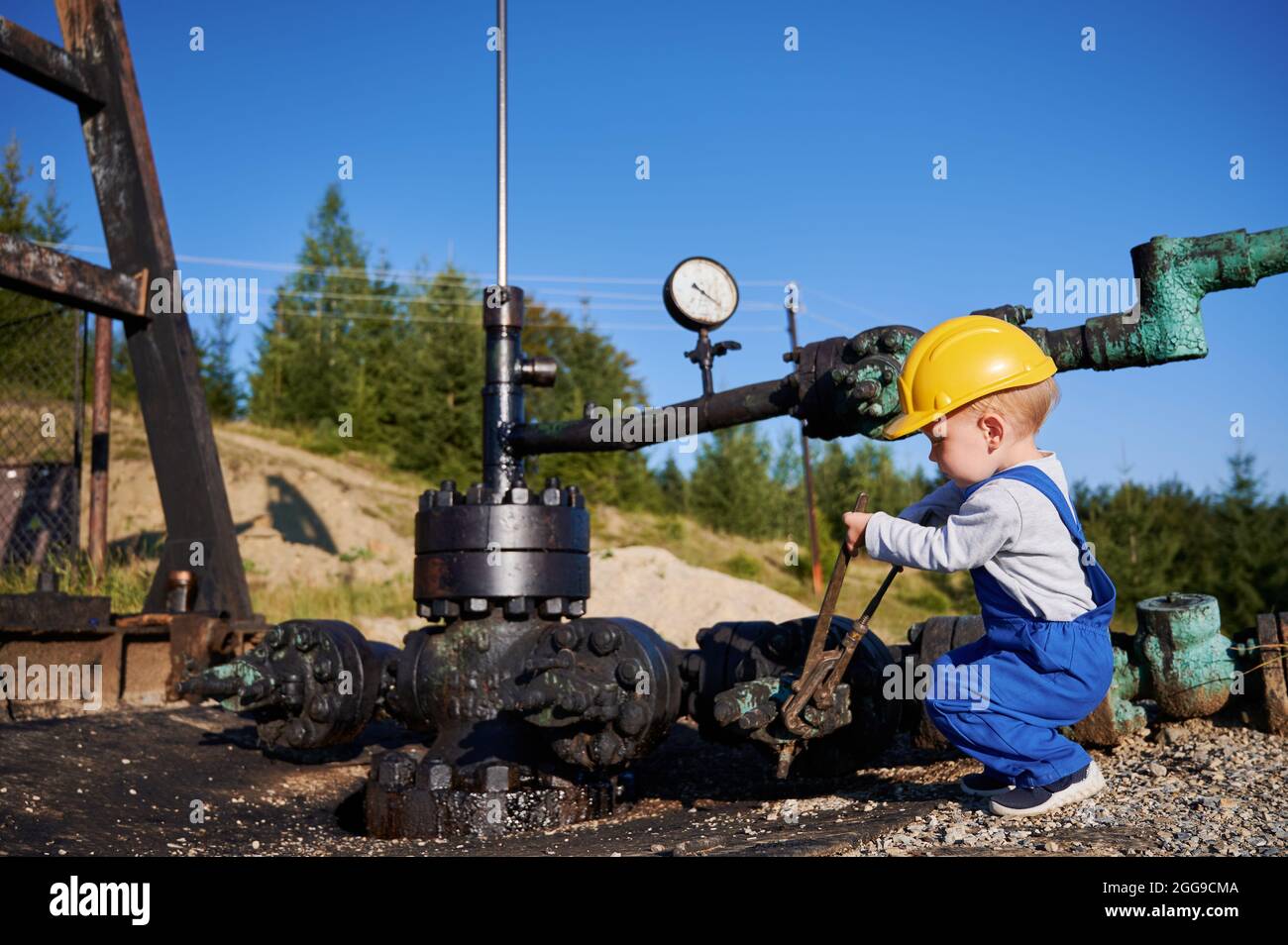 Adorable little boy in construction helmet using industrial wrench ...