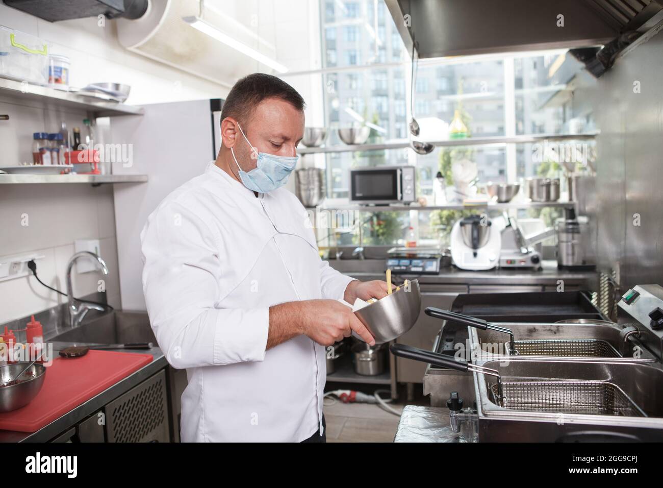 Male chef wearing medical face mask while working at restaurant kitchen ...
