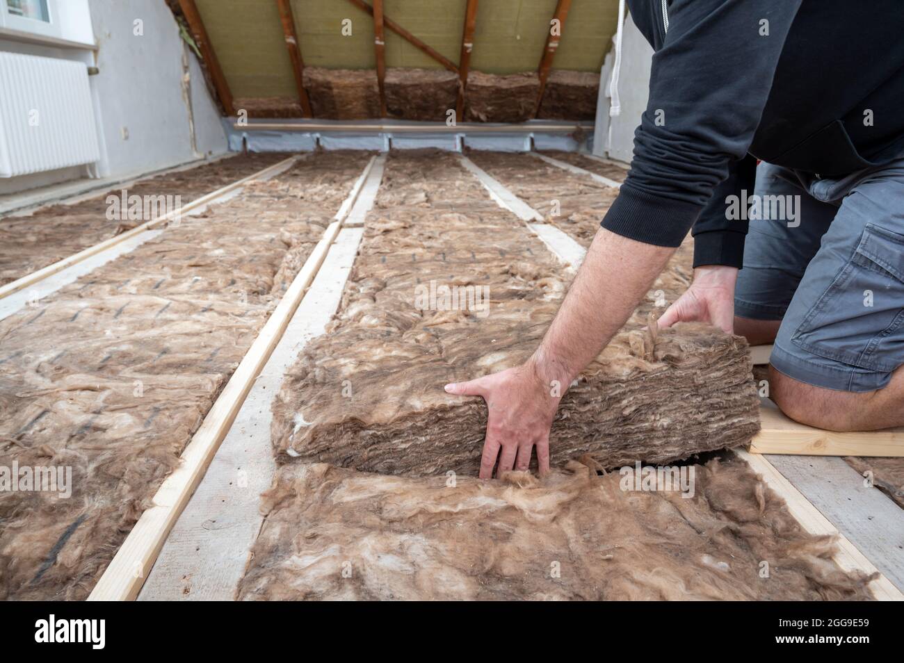 Man insulating the attic with rock wool Stock Photo - Alamy