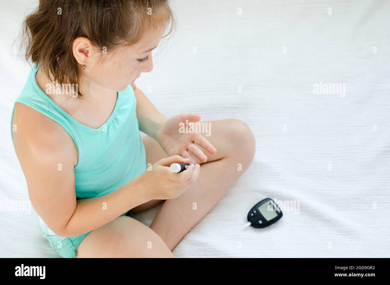 Little girl checking blood sugar level using lancelet and glucometer at ...