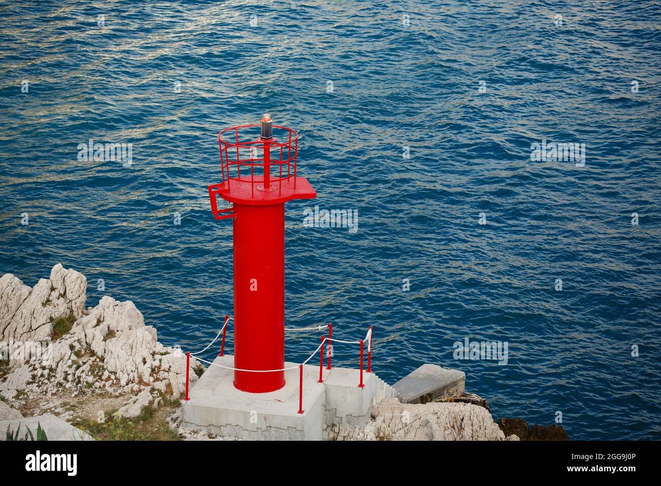 Red lighthouse on the rock cliff in the Adriatic sea water waves ...