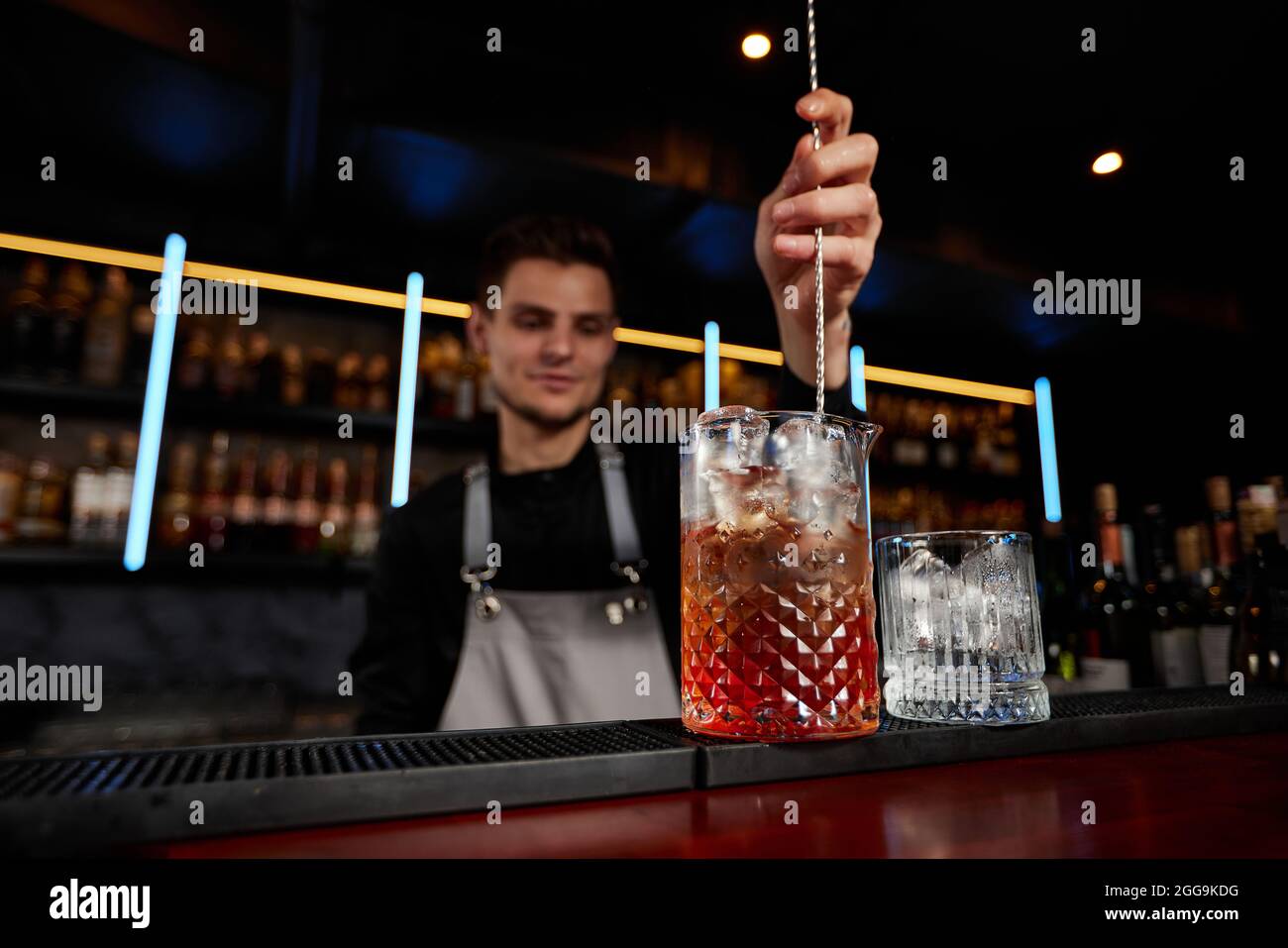 Barman stirring ice cubes in cocktail glass with spoon Stock Photo - Alamy