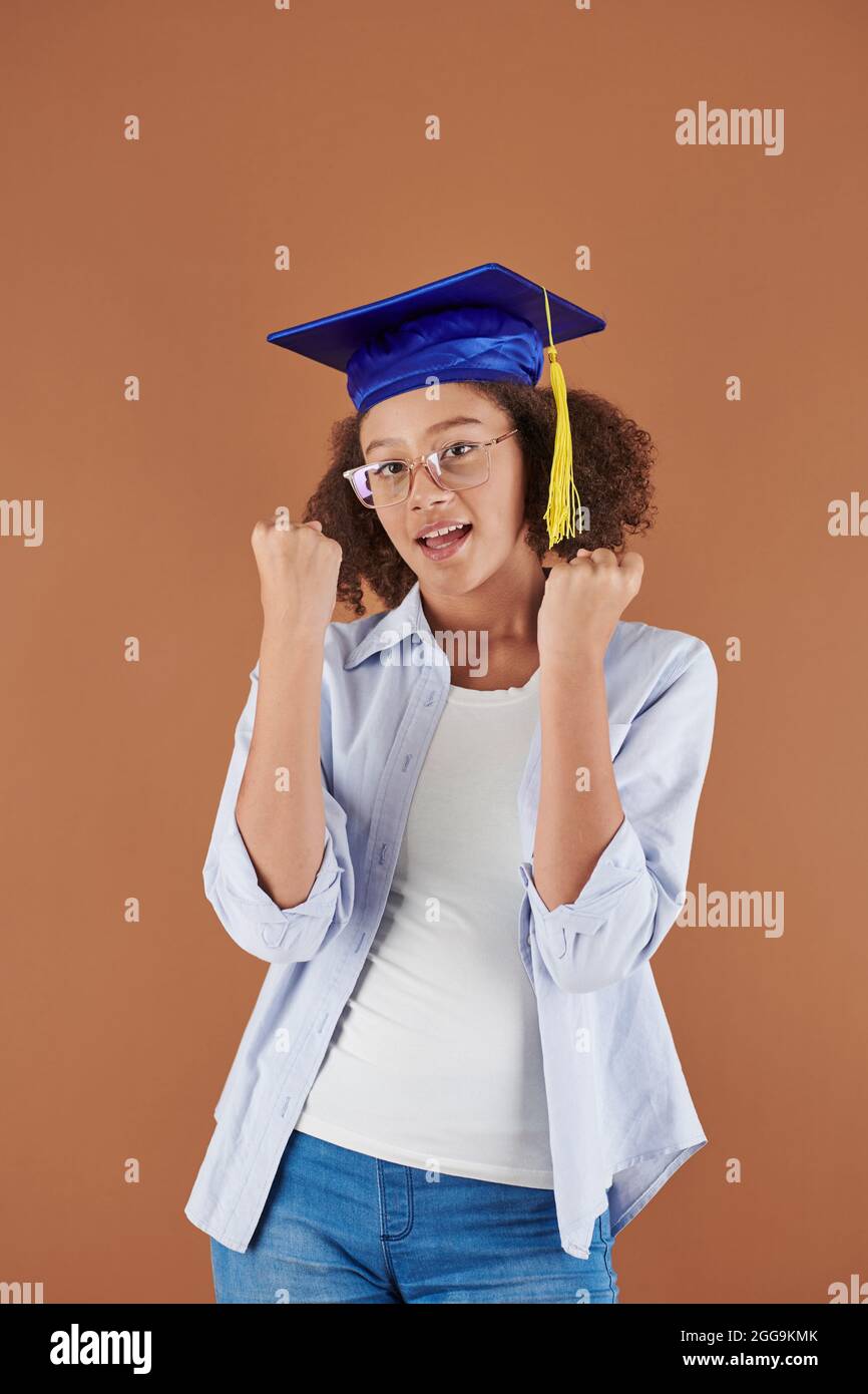 Excited teenage girl in student hat making fist pump celebrating ...