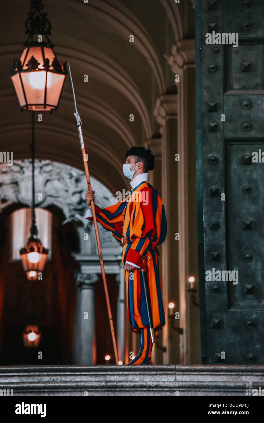 A vertical shot of a Swiss guard at St. Peter's Basilica wearing face ...