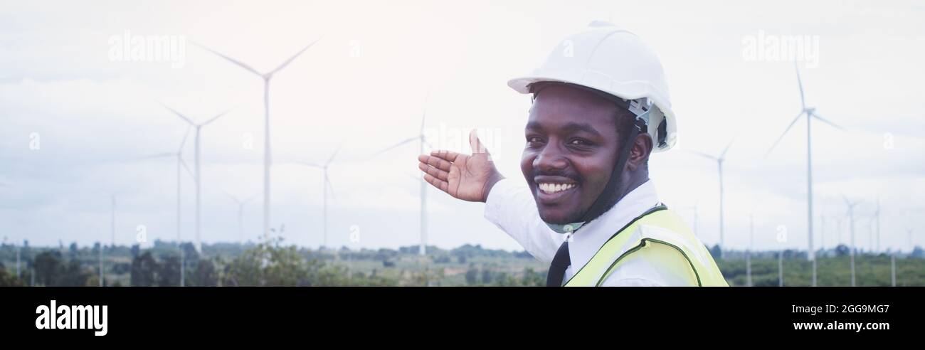 African male engineers working on site with wind turbine propeller and ...