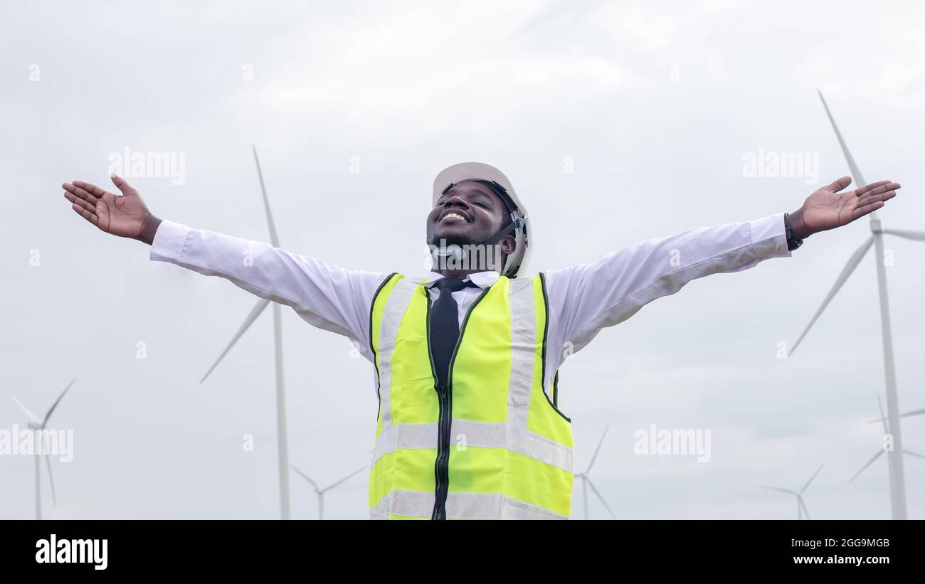 African male engineers working on site with wind turbine propeller and ...