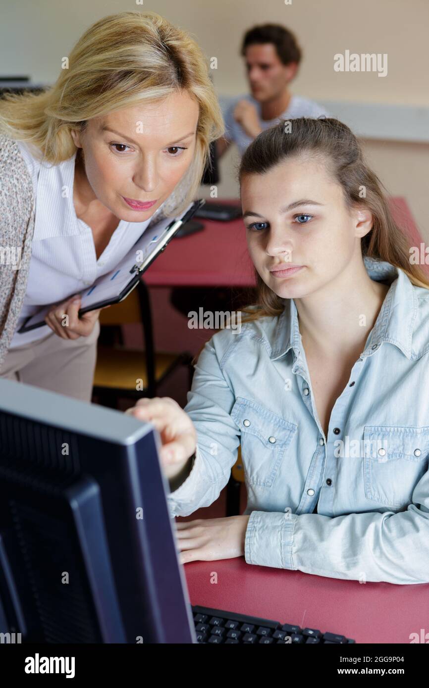 female teacher helping student on her computer lesson Stock Photo - Alamy