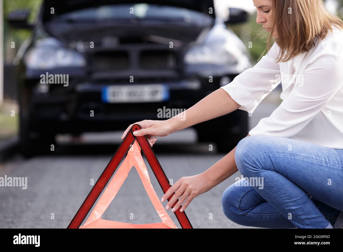 a broken car a triangle sign a woman Stock Photo - Alamy