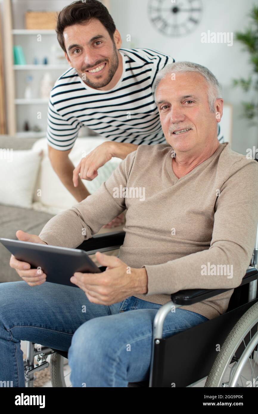 smiling man taking care of his eldery father in wheelchair Stock Photo ...