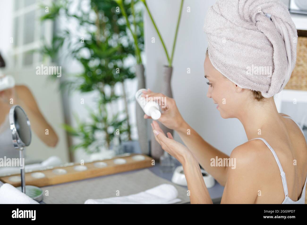 woman sat at mirror pouring beauty product onto hand Stock Photo - Alamy