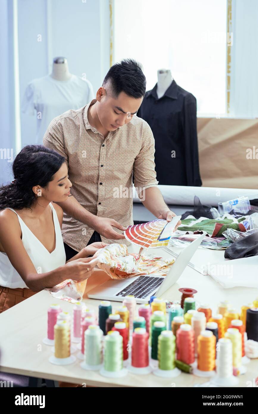 Team of young tailors using palette of color samples when choosing ...
