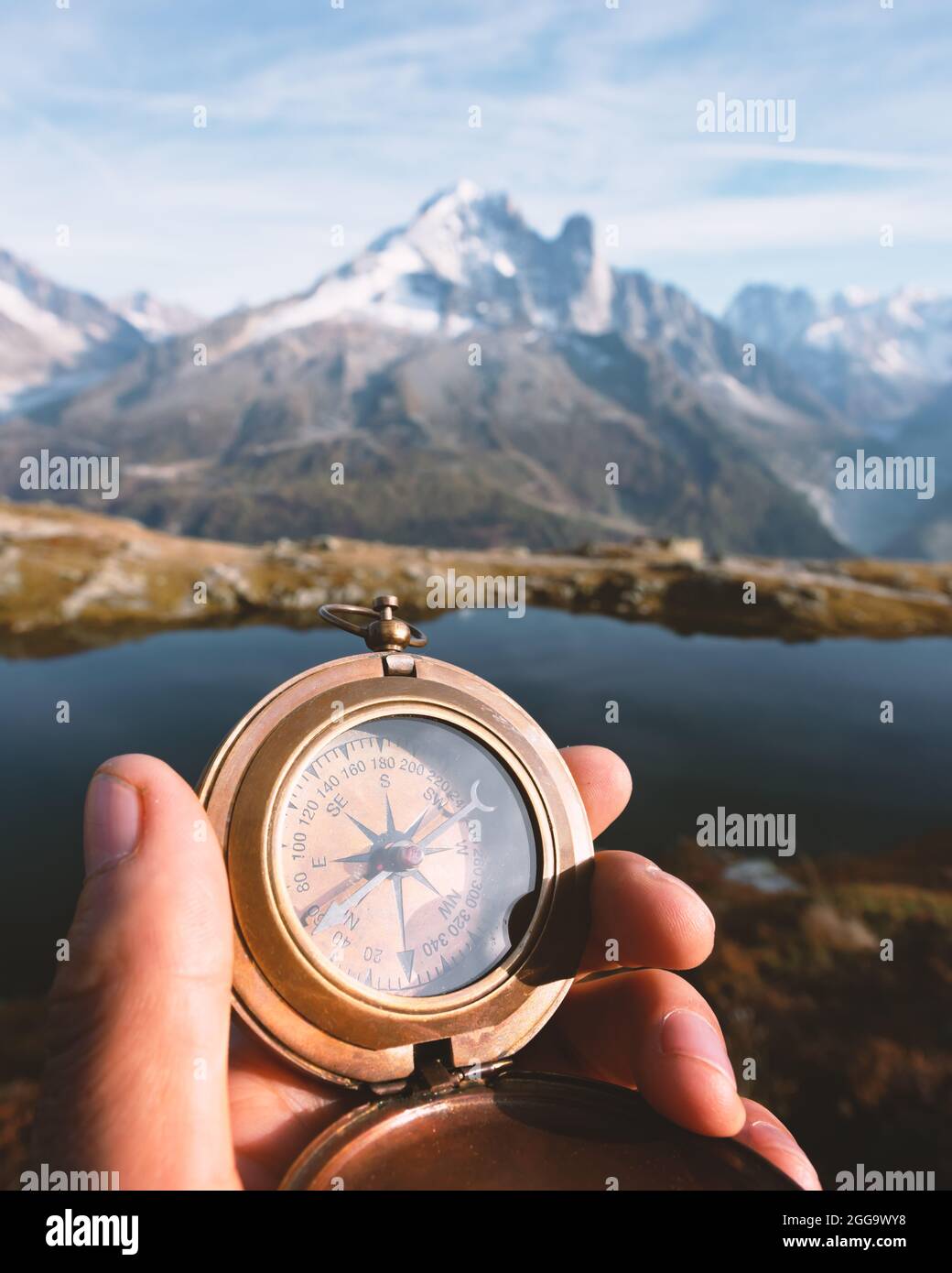 Man with compass in hand in high mountains near clear lake. Travel ...