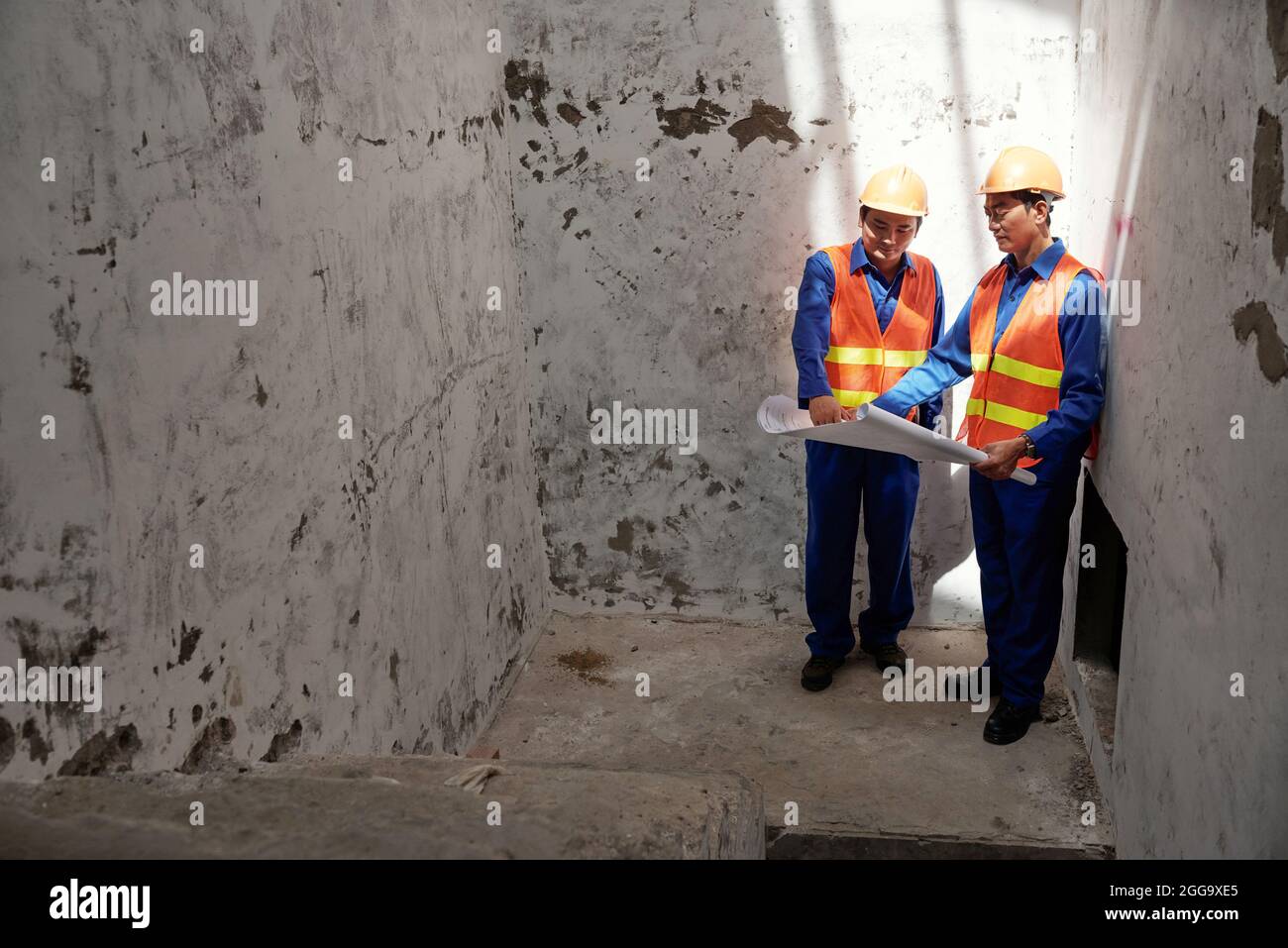 Head engineer and contractor in hard hats standing inside building ...