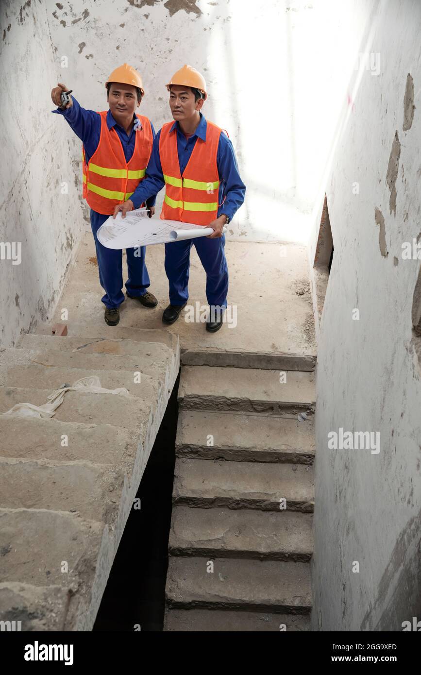 Construction engineers discussing serious problem with staircase unit ...