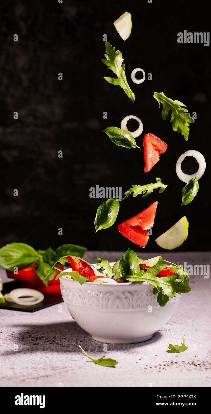 while bowl with falling salad ingredients Stock Photo - Alamy