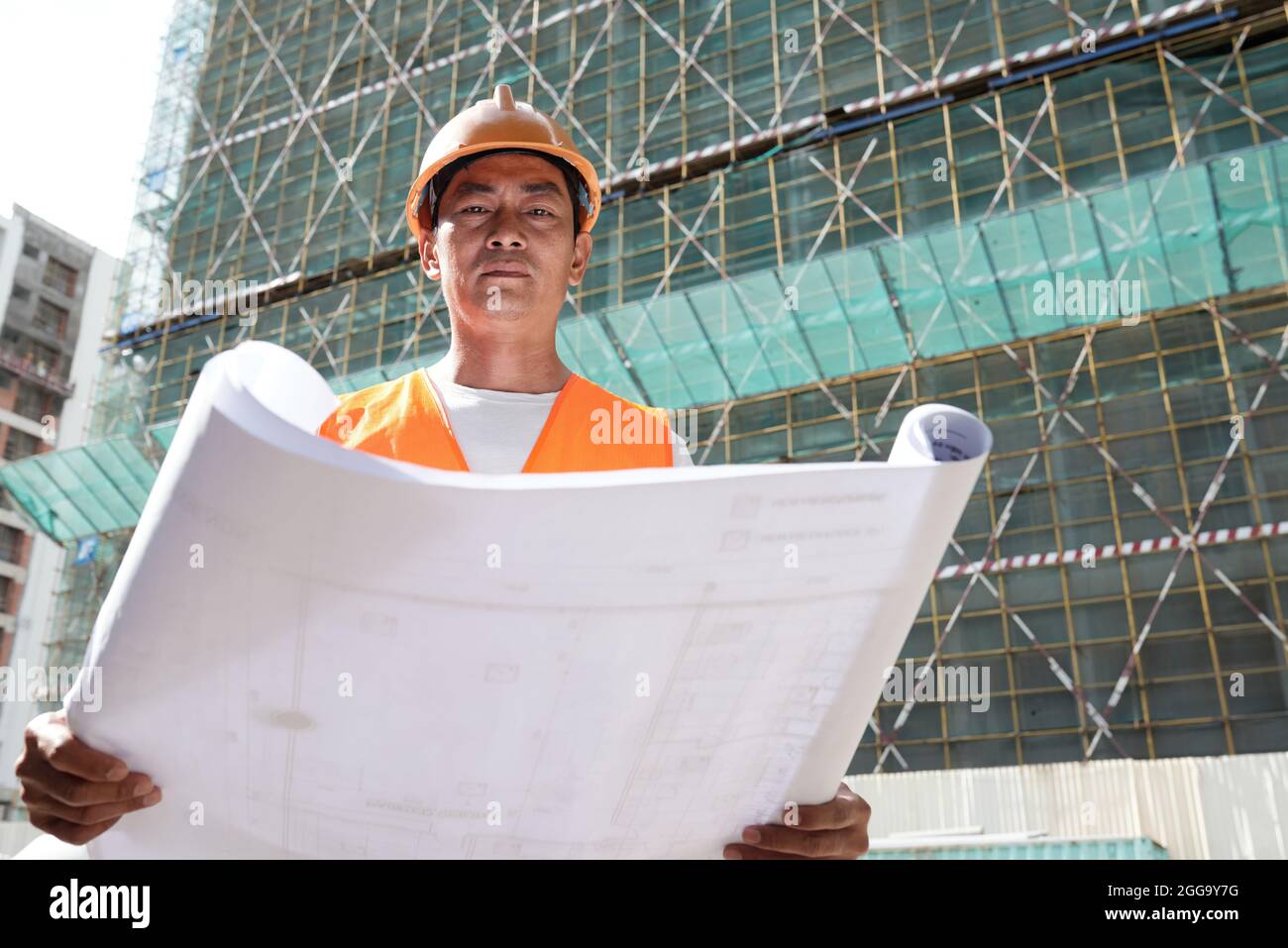 Serious builder working at construction site, he is rolling out ...